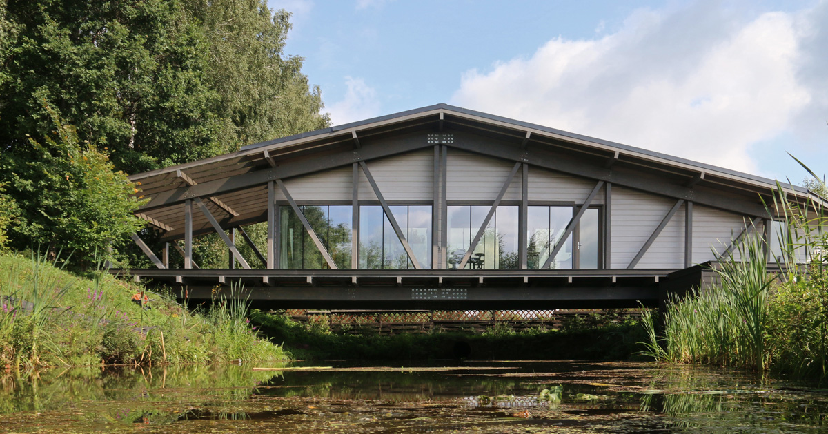 bridge house by bio-architects hovers over creek in russian forest