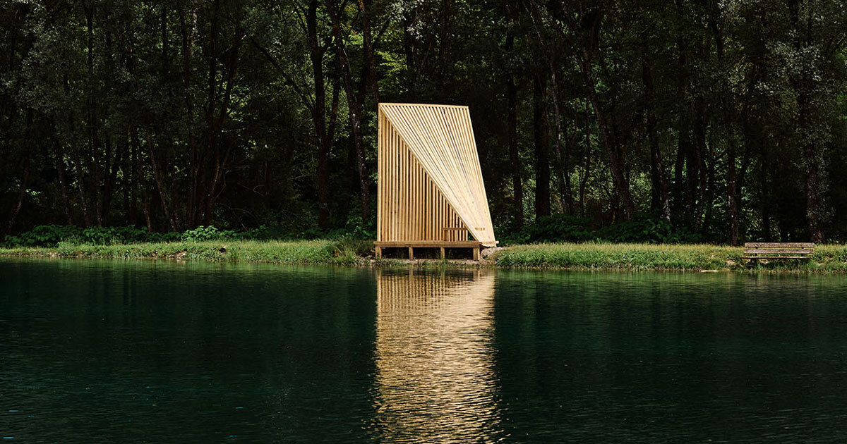 triangular wooden cabin unfolds on river's shore near alps