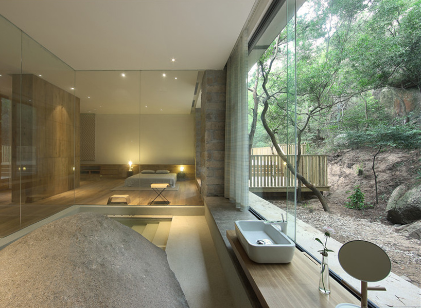 with glass walls that open to the surrounding forest and an exposed ...