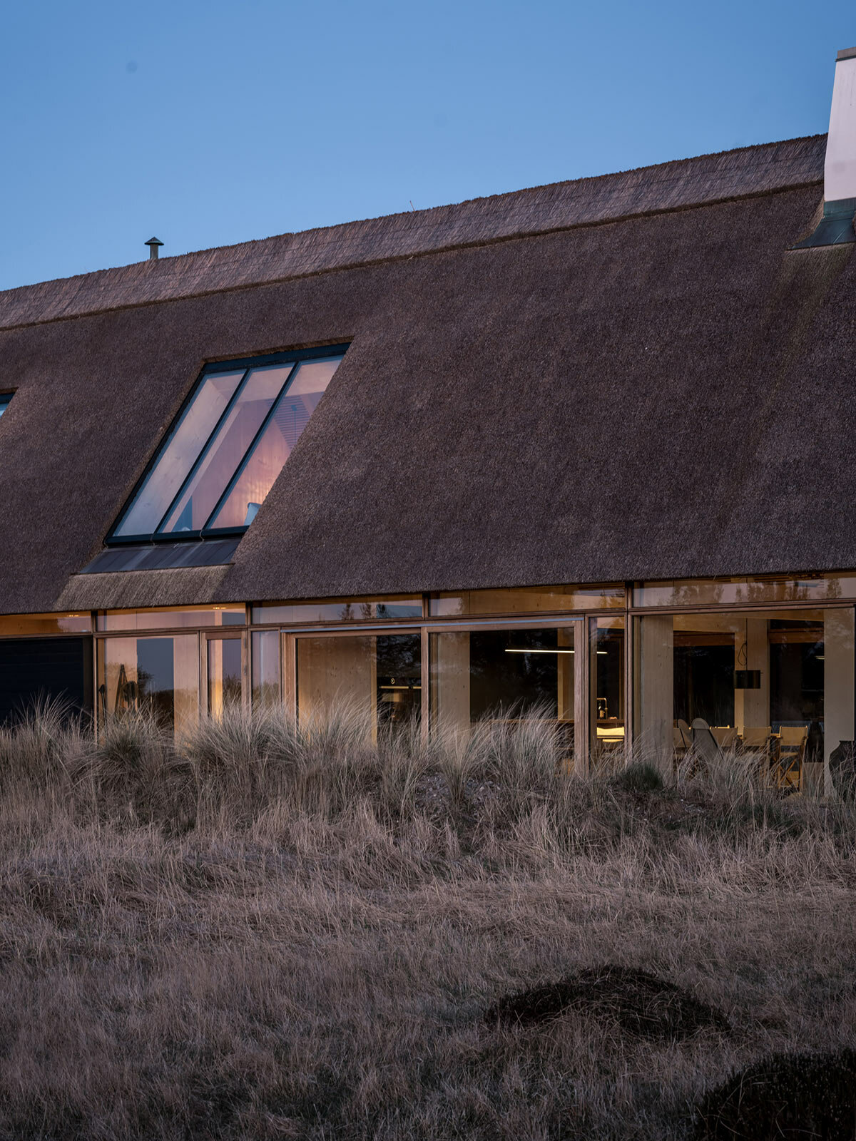 a thatched roof floats over PAX architects' skagen klitgård house