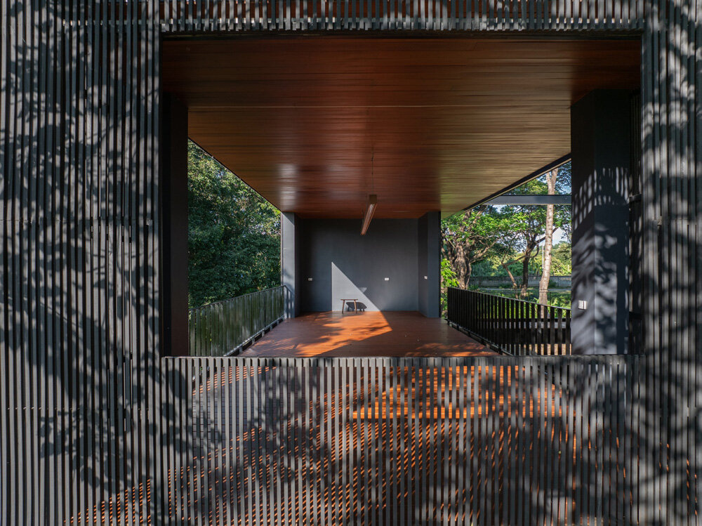 timber-clad residence settles on stilts within raintree forest in thailand