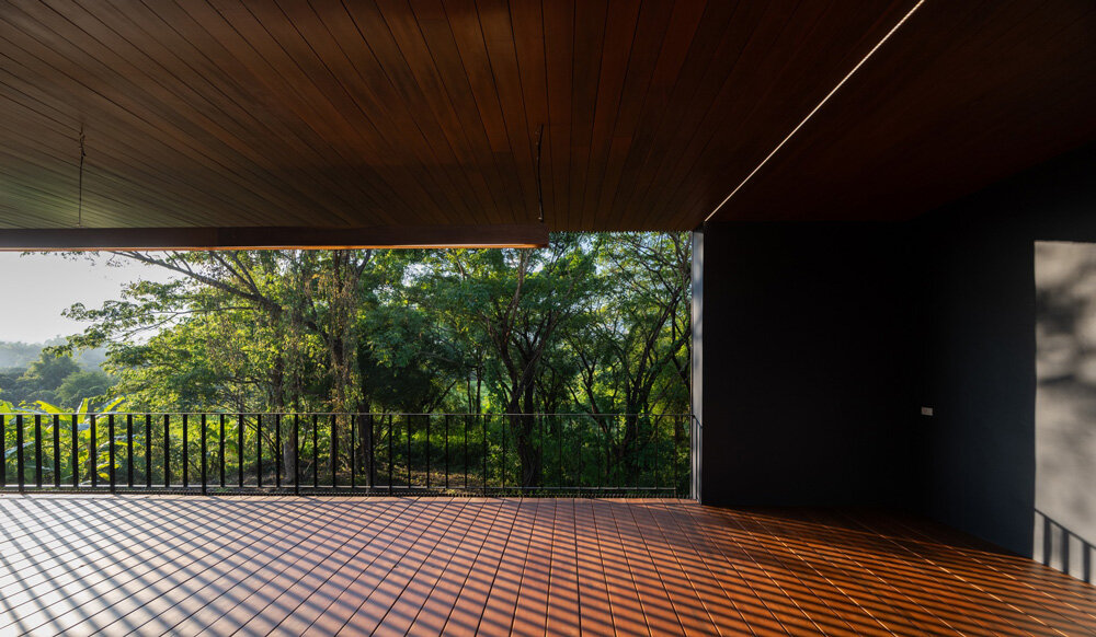 timber-clad residence settles on stilts within raintree forest in thailand