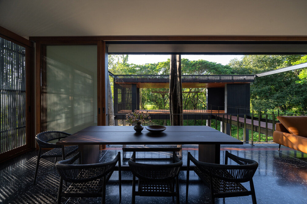 timber-clad residence settles on stilts within raintree forest in thailand